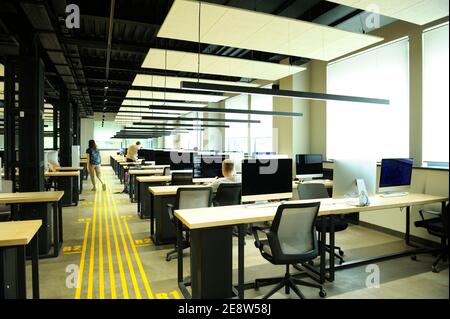 Large computer room with laptops on tables, blurred people working at ...