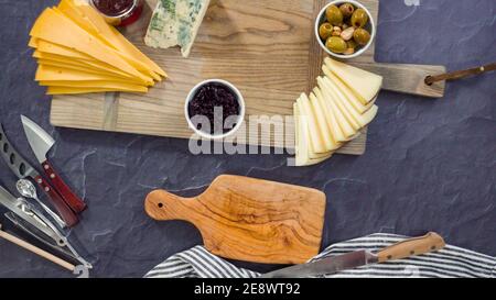 Flat lay. Arranging gourmet cheese, crakers, and fruits on a board for ...