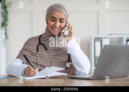 Happy muslim woman doctor having conversation on phone with patient ...