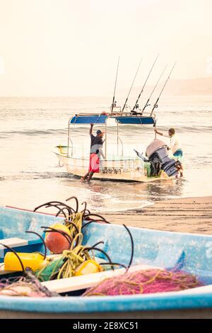 Fishermen push their boat out to sea at sunset Stock Photo - Alamy