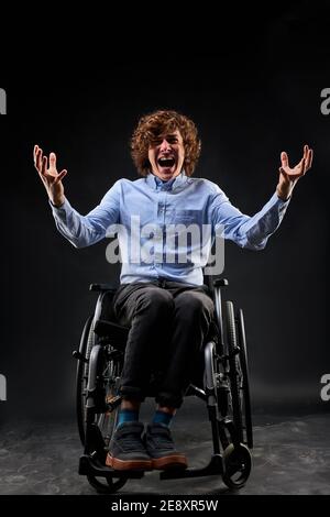 disabled man scream by despair sitting on wheelchair isolated on black ...