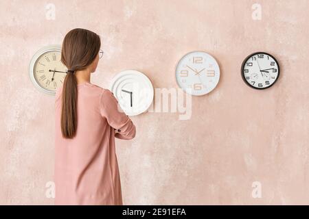 Young woman looking at different clocks Stock Photo - Alamy