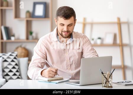 Young businessman writing with a pencil and surfing the internet on a ...