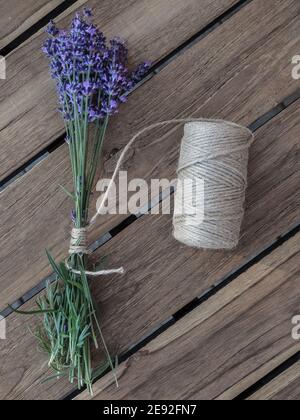 Bunch of lavender flowers bound by cord on wooden table. Blurred grass ...