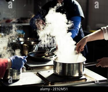 Chef cooking soup and water evaporating from a pot at a restaurant ...