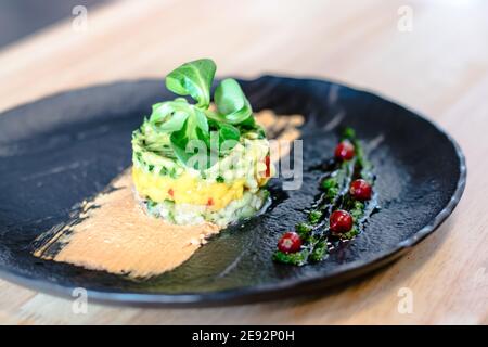 Colorful avocado tartar on a black plate at a restaurant Stock Photo ...