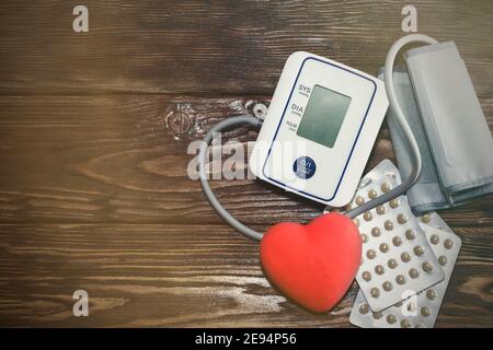White electric tonometer, red heart and pills, on wooden table Stock ...