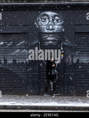 A girl walks past a wall with street art in East Harlem on a sunny ...