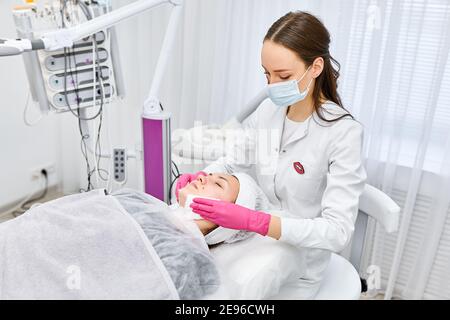 Hands of skillful beautician cleaning female face with cotton pad Stock ...