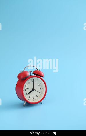 Red retro alarm clock isolated on a blue background Stock Photo - Alamy