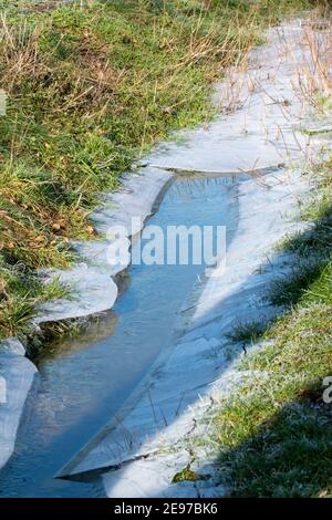 The trench is frozen over and covered with ice. It is winter and severe ...