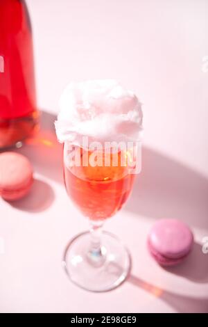 Bottle and glass with tasty cotton candy cocktail and party hats on ...