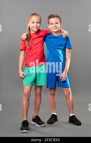 Adorable female child wrapping arm around brother shoulder and smiling ...