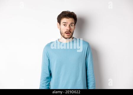 Confused caucasian guy drop jaw and stare startled at camera, standing ...