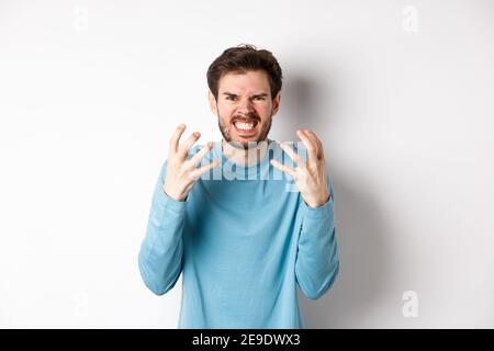Angry caucasian man shaking hands and grimacing, looking with mad face ...