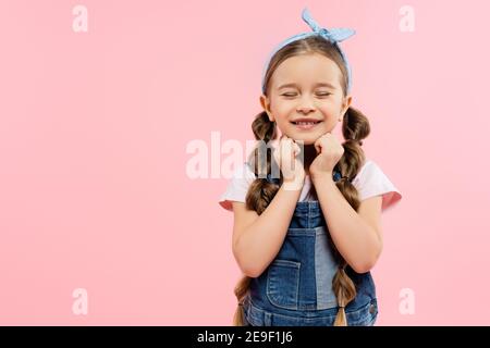 pleased kid with closed eyes smiling isolated on pink, banner Stock ...