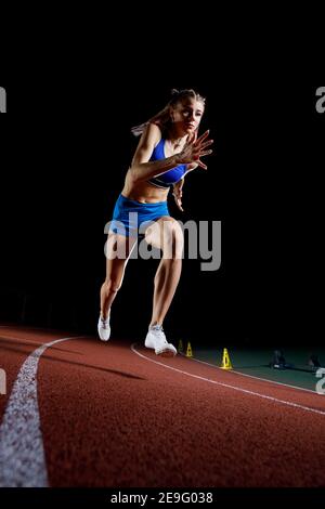 Female athlete sprinting off starting line at stadium Stock Photo - Alamy