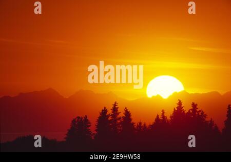 The setting sun over Alaska's Cook Inlet on a summer evening in South ...