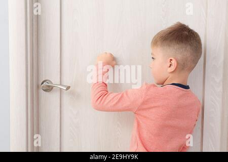 Cute little boy knocking at the door Stock Photo - Alamy