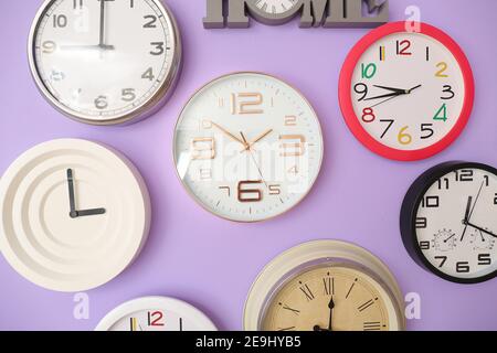 Different clocks hanging on color wall Stock Photo - Alamy