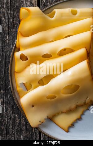 top view of slices of cheese on crumpled paper and ripe red grapes on ...