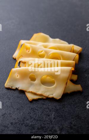 Sliced hard cheese on black table Stock Photo - Alamy