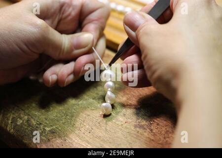 Pearl necklace knotting and threading at the jeweler Stock Photo - Alamy