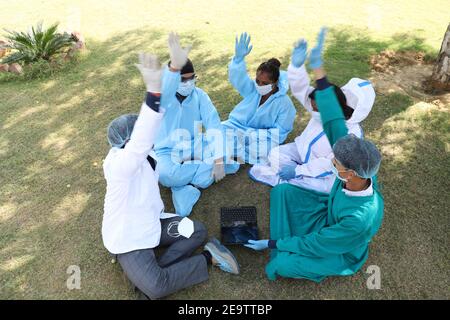 The Indian doctors high fiving each other while sitting on green grass ...