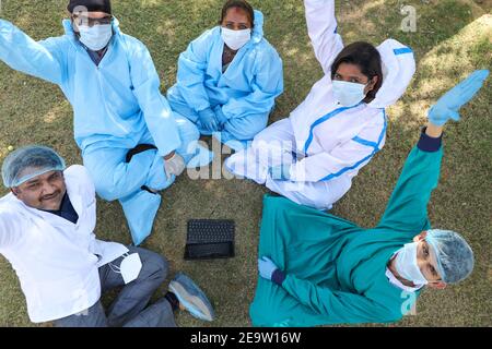The Indian doctors with raised hands sitting on green grass - teamwork ...