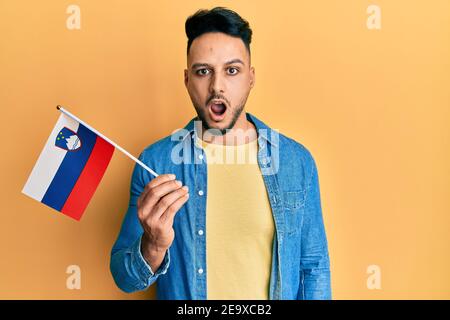 Young arab man holding slovenia flag smiling happy pointing with hand ...