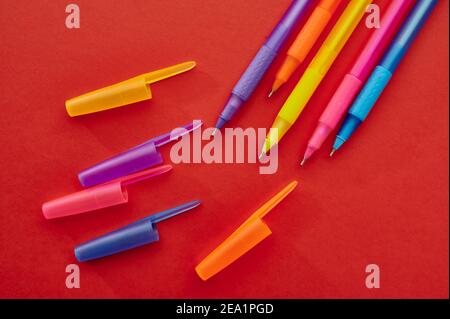 Colorful pens with caps closeup, red background. Office stationery ...