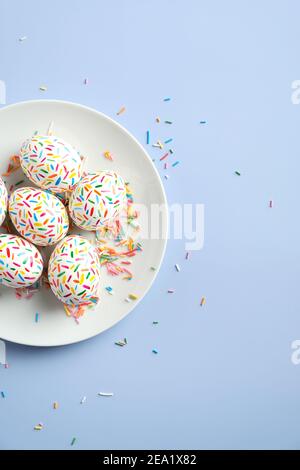 Colorful eggs on a plate, bright green blue background, Easter concept ...