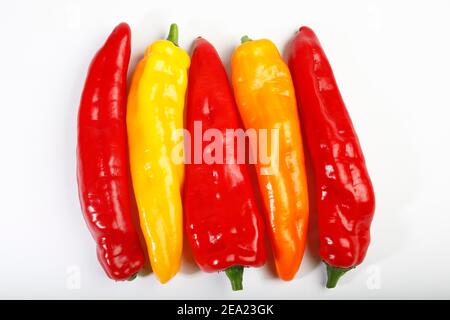 Red, Orange and yellow sweet pointed peppers on a wooden cutting board ...
