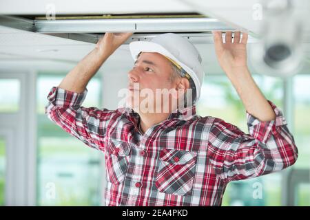 man install suspended ceiling in house Stock Photo - Alamy