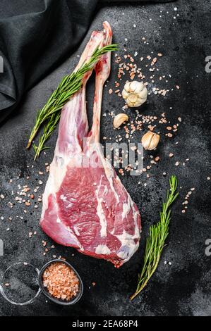 Raw goat leg with salt and garlic. Farm meat. Black background. Top ...