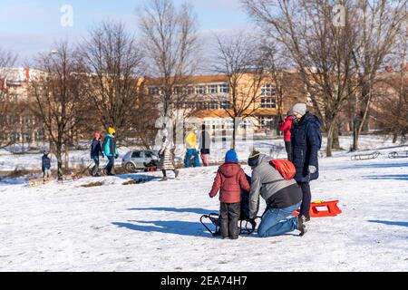 POZNAN, POLAND - Jan 30, 2021: Woman and child sitting on wooden sled ...
