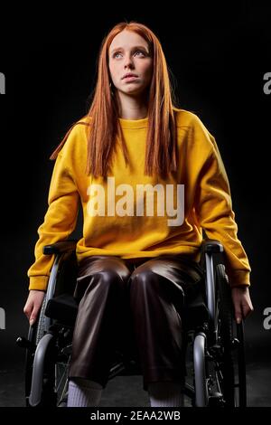 A young brunette woman with a disability sits in a wheelchair, holding ...