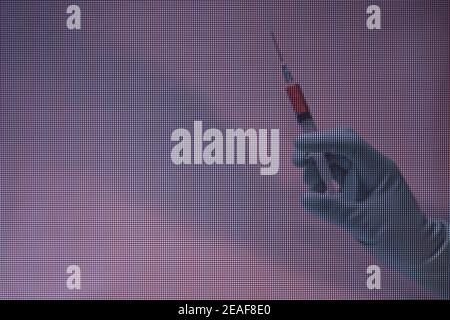 Beautiful hand holding creative syringe with red vaccine in the neon ...