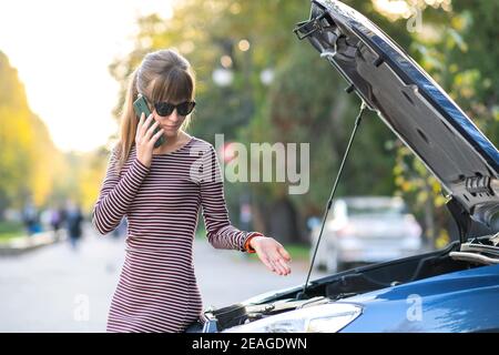 Unhappy young woman waiting angrily while her friend is talking happily on sellphone with ...