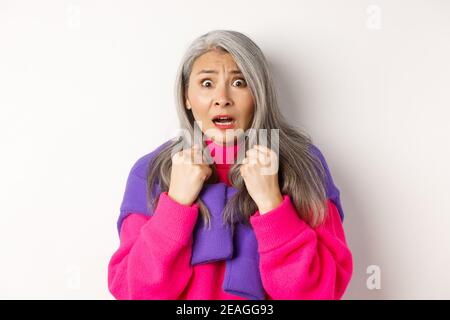Close up of scared asian senior woman gasping, looking frightened and ...