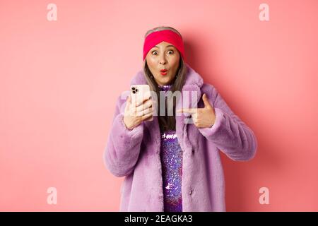 Awesome promo offer. Amazed asian girl points up, say wow, impressed ...