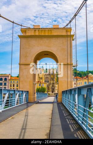 Cathedral in Vienne viewed behind a pedestrian bridge over river Rhone ...