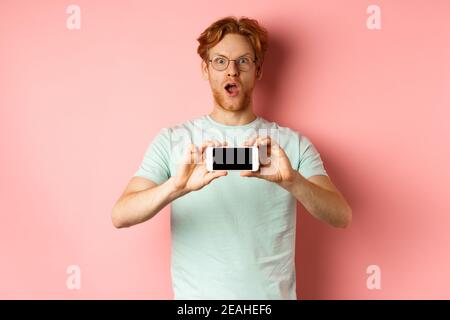 Amazed redhead man gasping and staring with awe at camera, showing ...