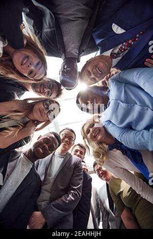 multinational business team looking down putting hands together Stock ...
