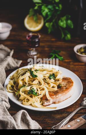 Pork chop steak and tagliatelle with capers and lemon zest Stock Photo ...