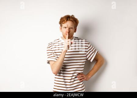 Angry redhead man looking displeased and hushing at camera, making shh ...