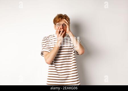 Scared redhead guy screaming terrified, holding hands on face from fear ...