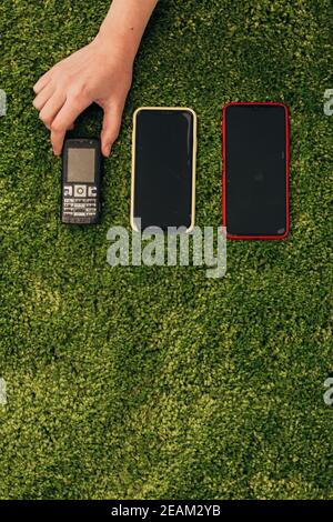 The Human Hand Picks an Old Phone That Lies Near New Smartphones Stock ...
