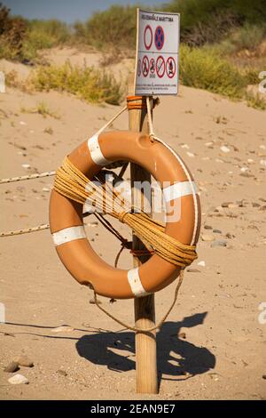 An orange lifebuoy, safety ring hanging on bamboo fence wall background, center view. Rescue ...