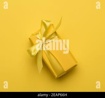 rectangular box with a gift wrapped in yellow paper and tied with a ...